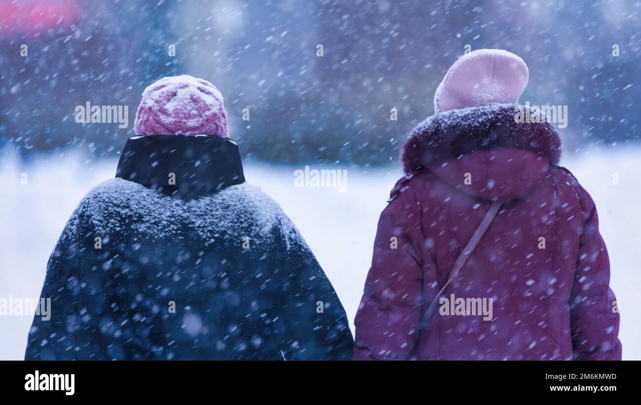 Two people on the street in winter clothes during snowfall ...