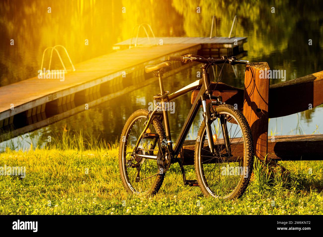 Modern sport mountain bike leaning against wooden bench at lakeside ...