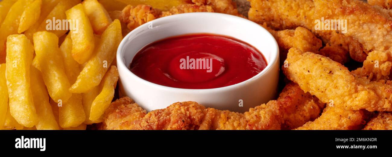 Chicken tenders panorama, crispy boneless meat pieces with a red dip ...