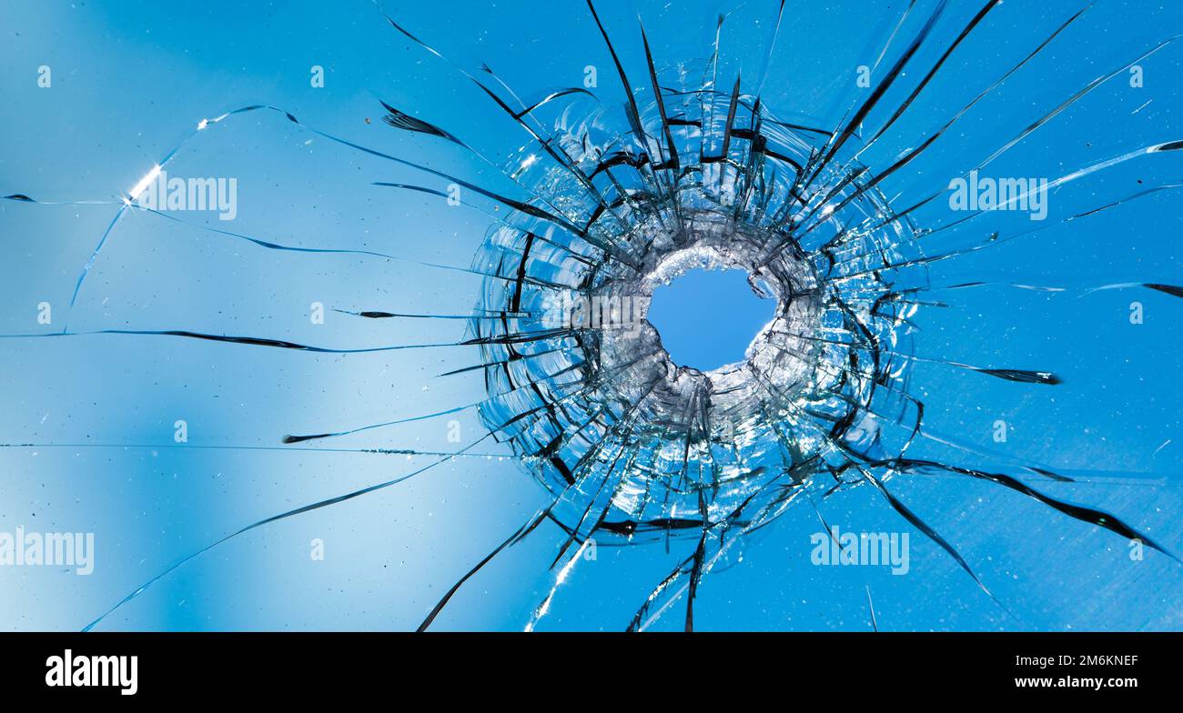 Bullet holes in the window against the blue sky. Consequences of ...
