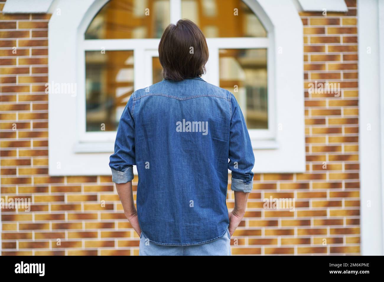 Back view of a man standing alone looking at old town building while ...