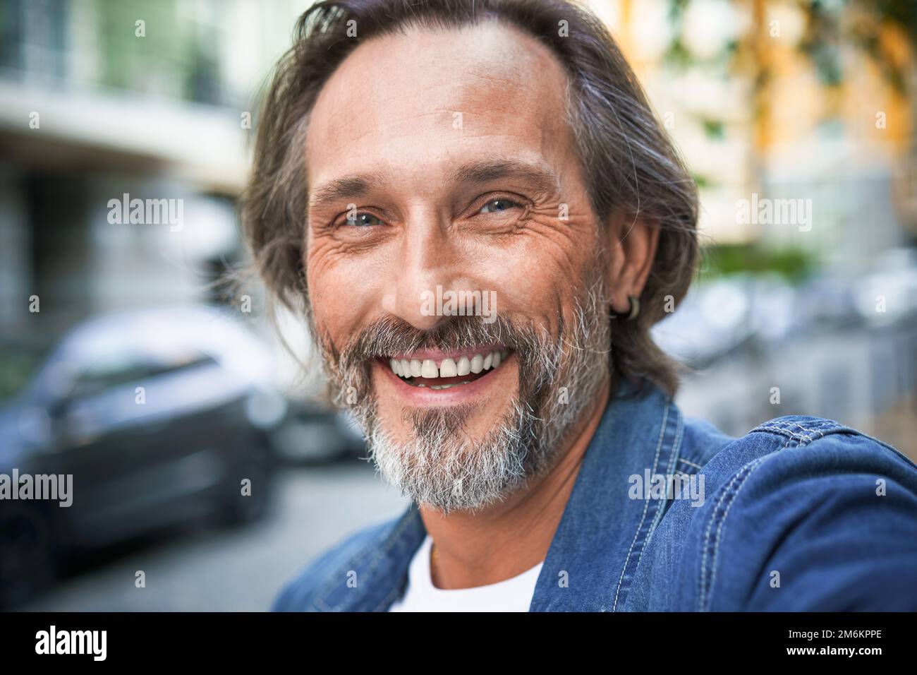 Happy senior man on street of european city making selfie using mobile ...