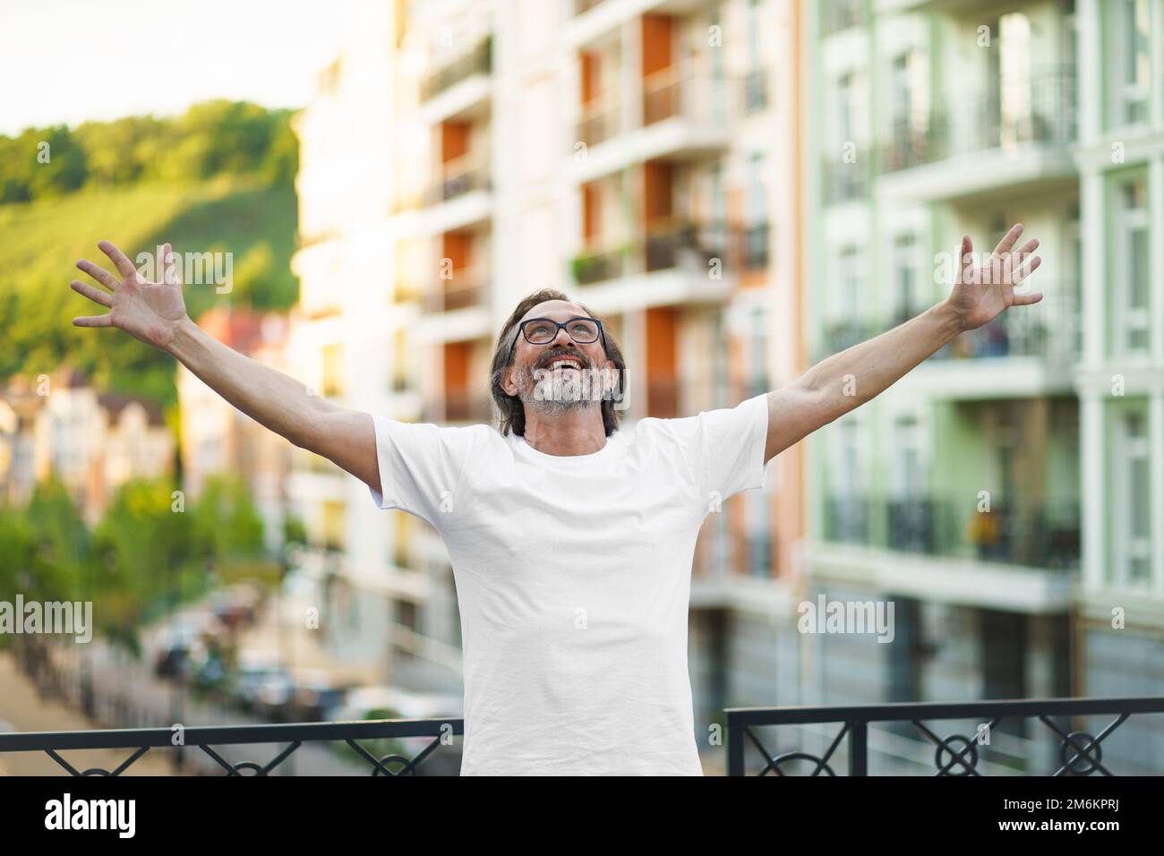 Senior man in glasses praising God standing outdoors with hands spread ...