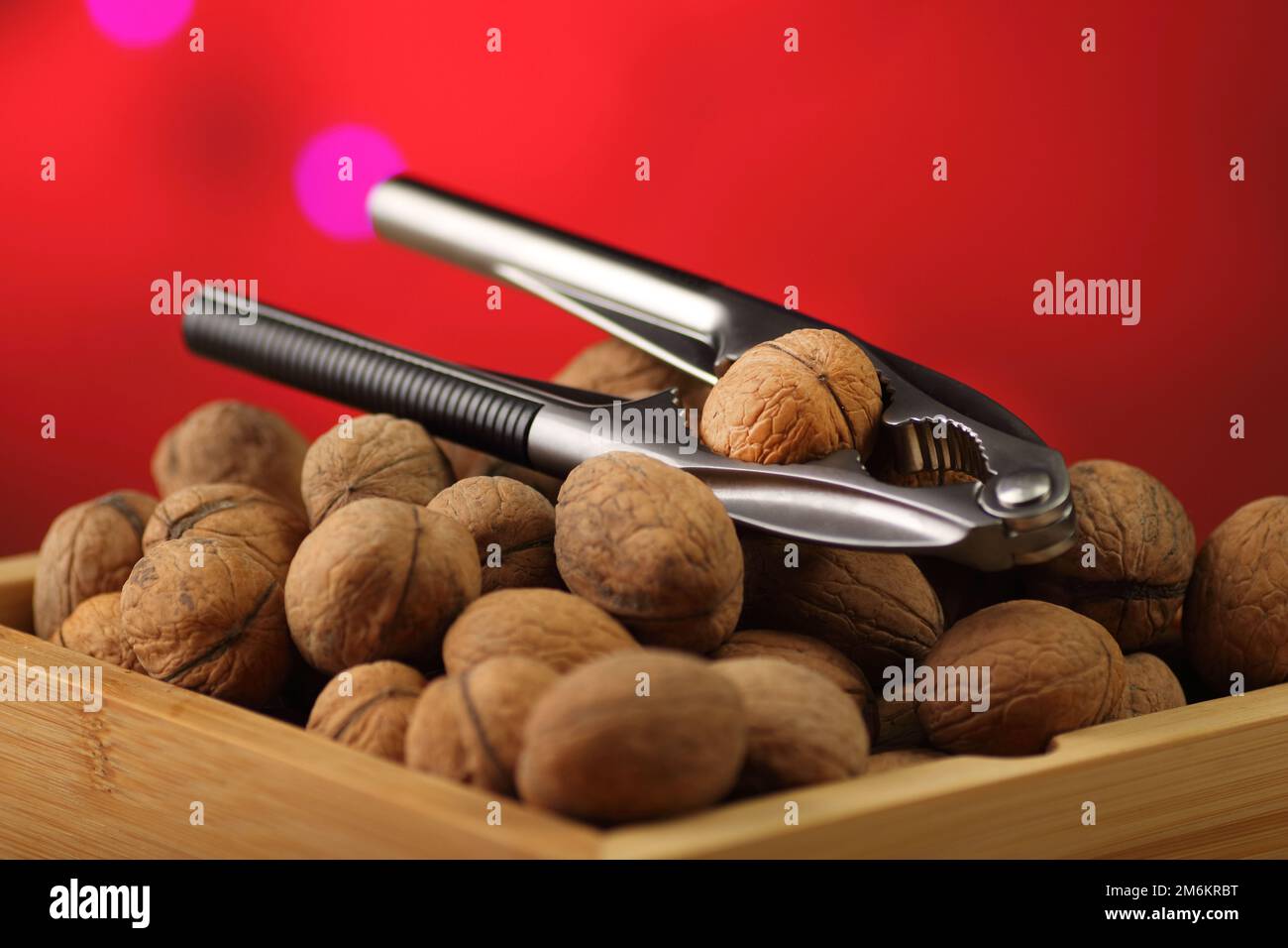 metal nutcracker on a bowl with nuts and colored background Stock Photo ...