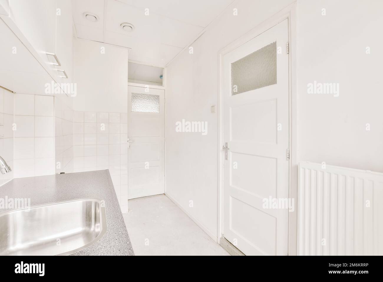 an empty kitchen area with white walls and floor tiles on the wall ...
