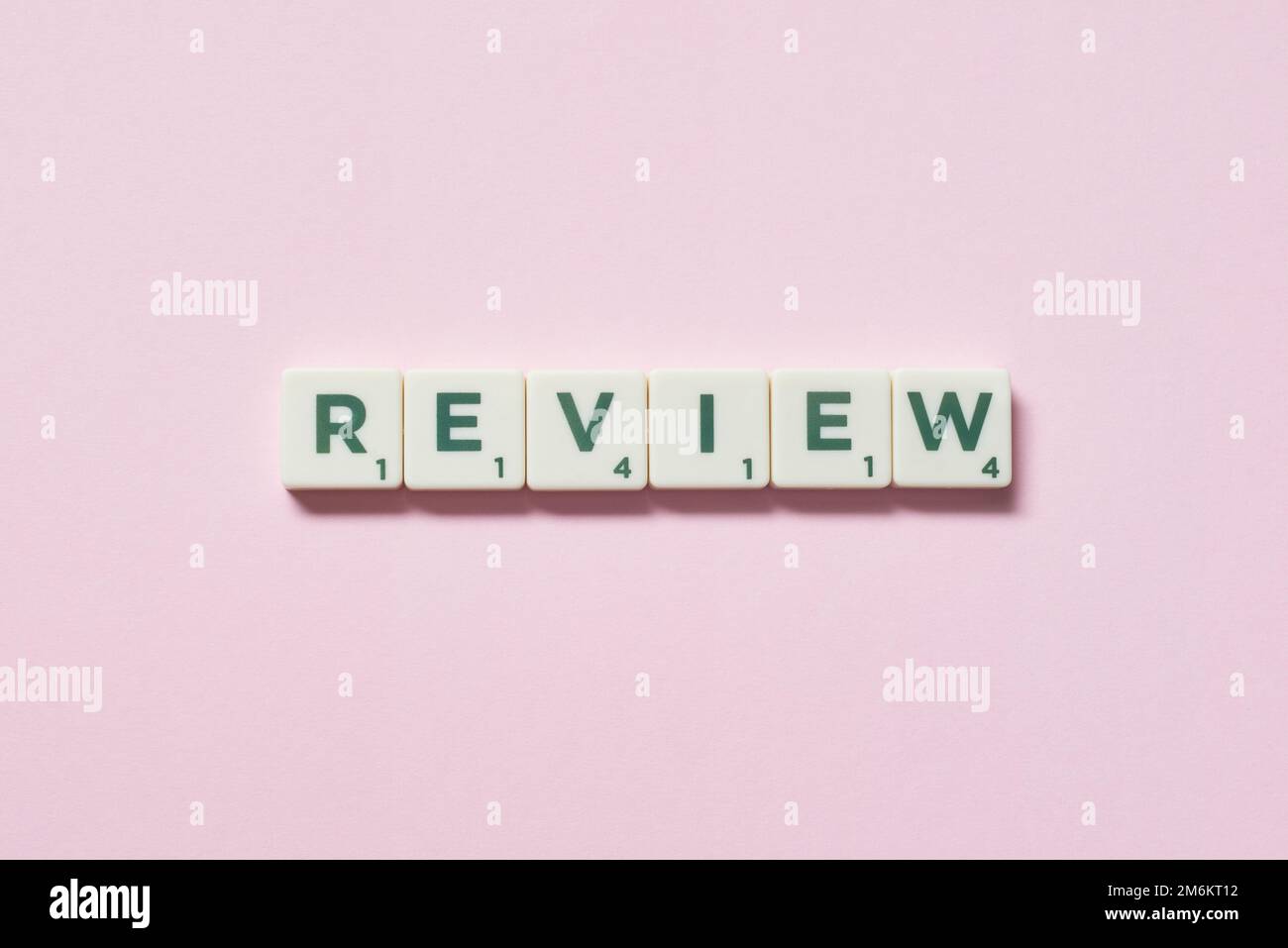 Review formed of scrabble blocks on pink background Stock Photo - Alamy