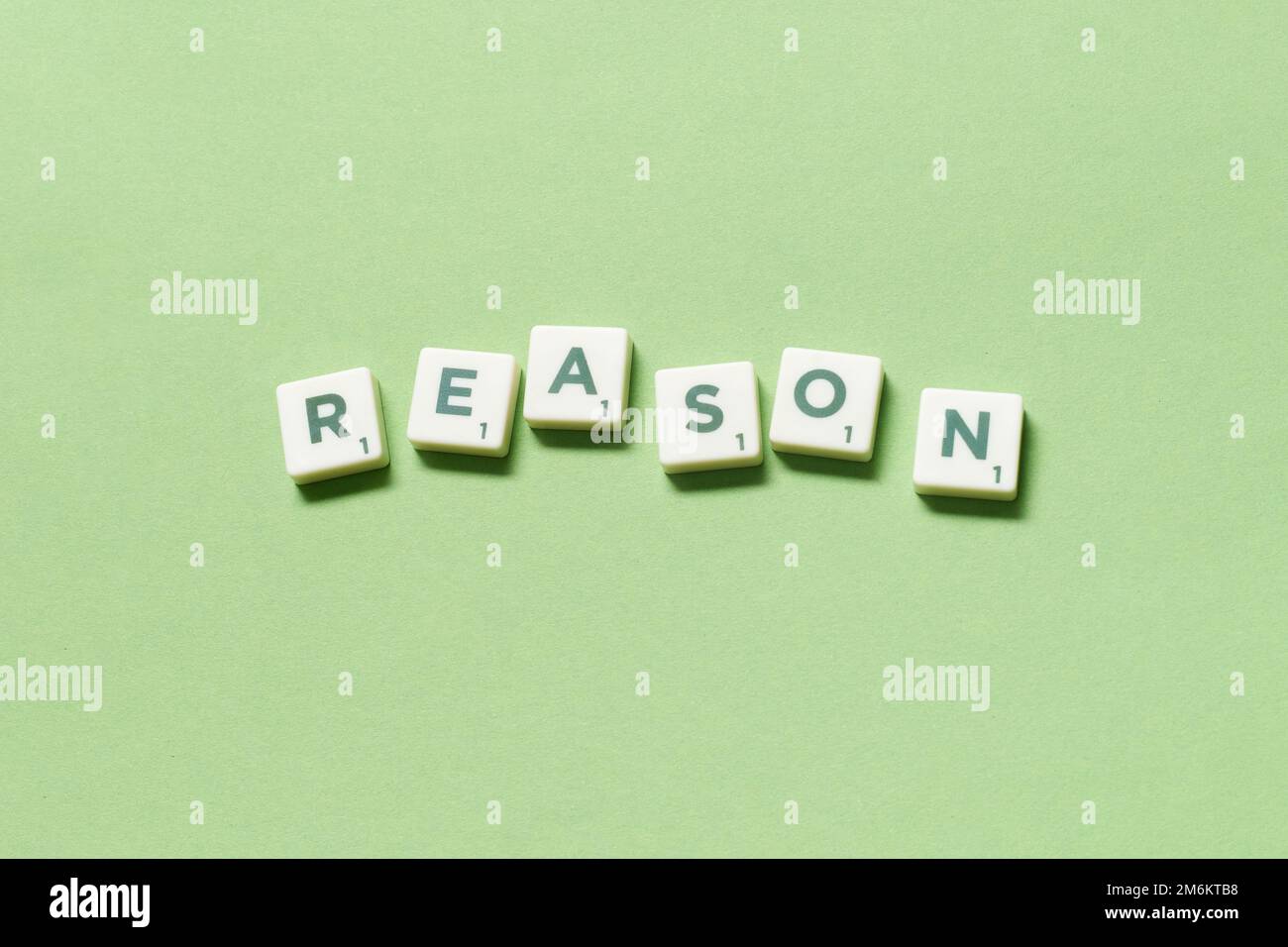 Reason formed of scrabble tiles on green background Stock Photo - Alamy