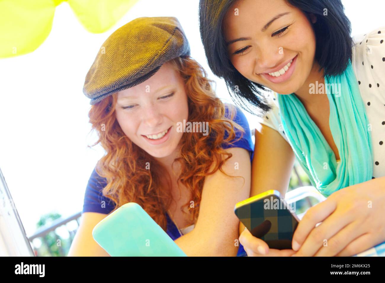 Modern communication. Two teenage girls sitting outside texting on ...