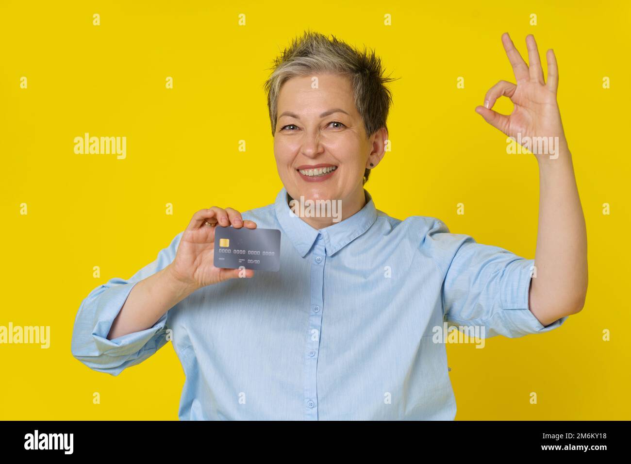 Holding credit, credit card grey haired woman gesturing OK with other ...