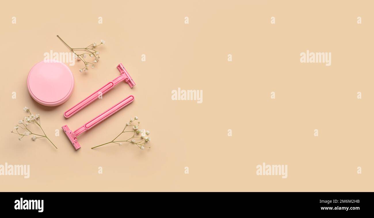 Razors for hair removing, jar of cosmetic cream and flowers on beige ...