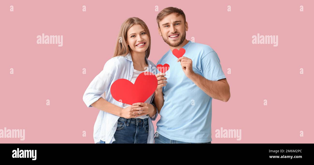 Happy young couple with red hearts on pink background Stock Photo - Alamy