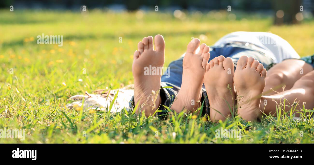 Happy barefoot couple lying on grass in park Stock Photo - Alamy