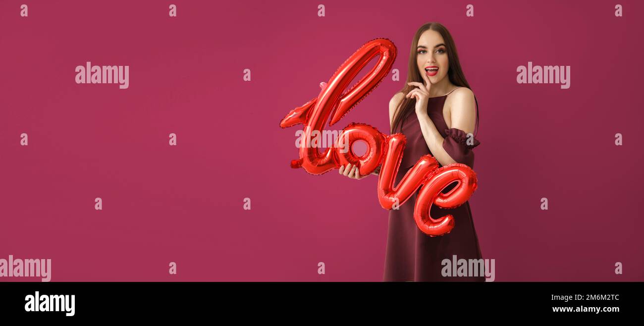 Beautiful young woman with balloon in shape of word LOVE on color ...