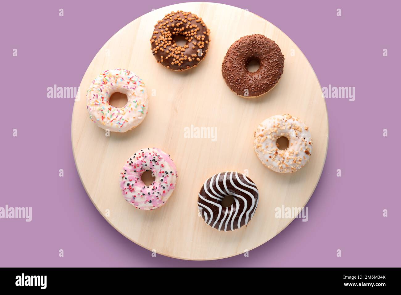 Wooden board with different sweet donuts on color background Stock ...