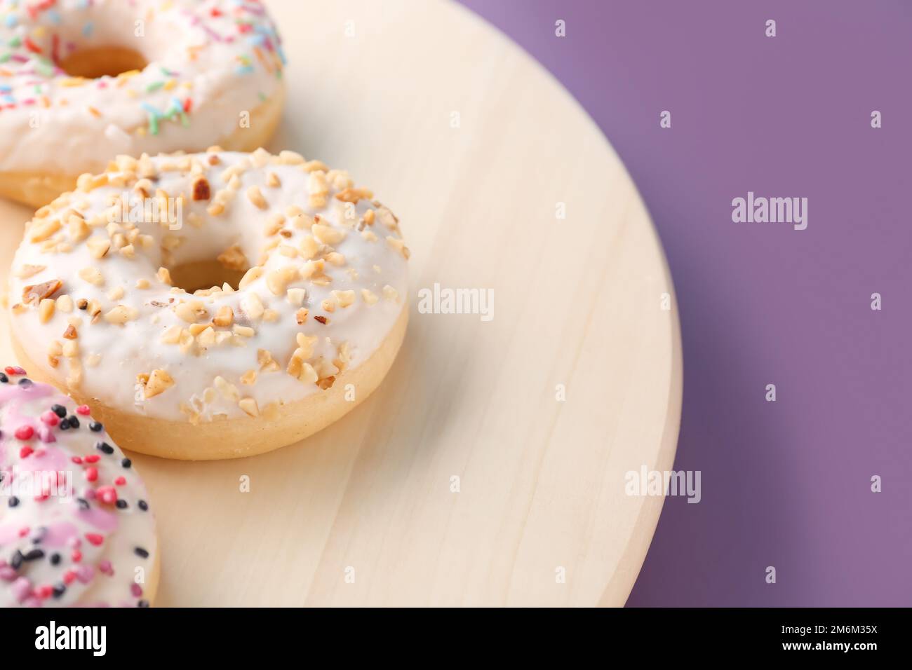 Wooden board with delicious donuts on color background, closeup Stock ...