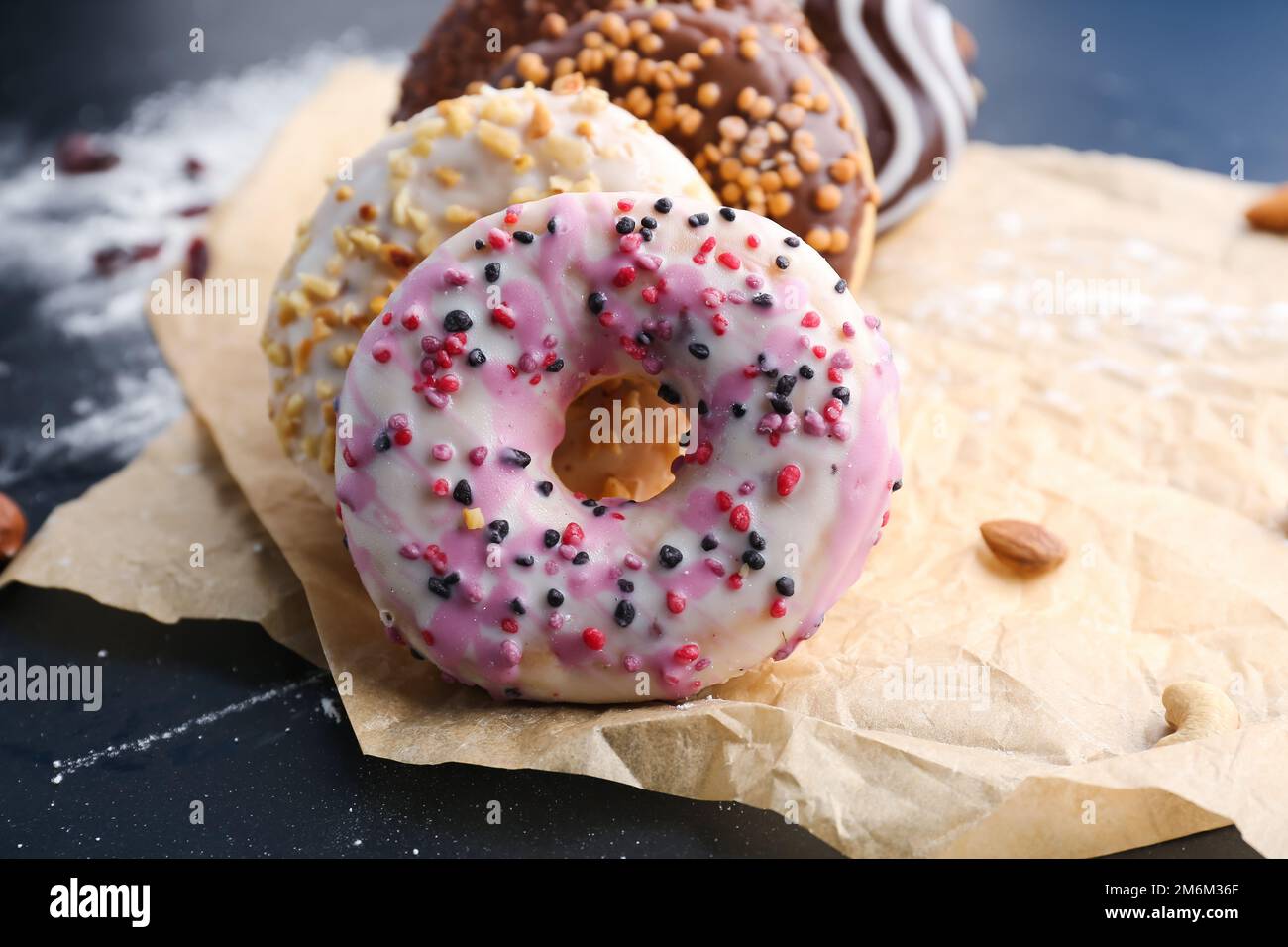 Sheet of baking paper with tasty donuts on dark background, closeup ...