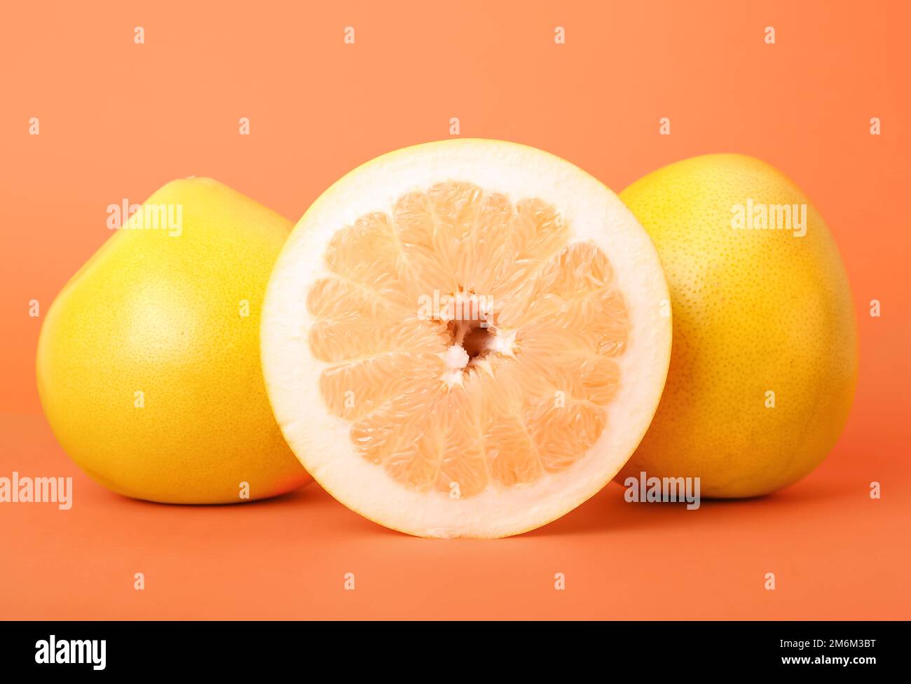 Whole and cut sweet pomelo fruit on orange background Stock Photo - Alamy
