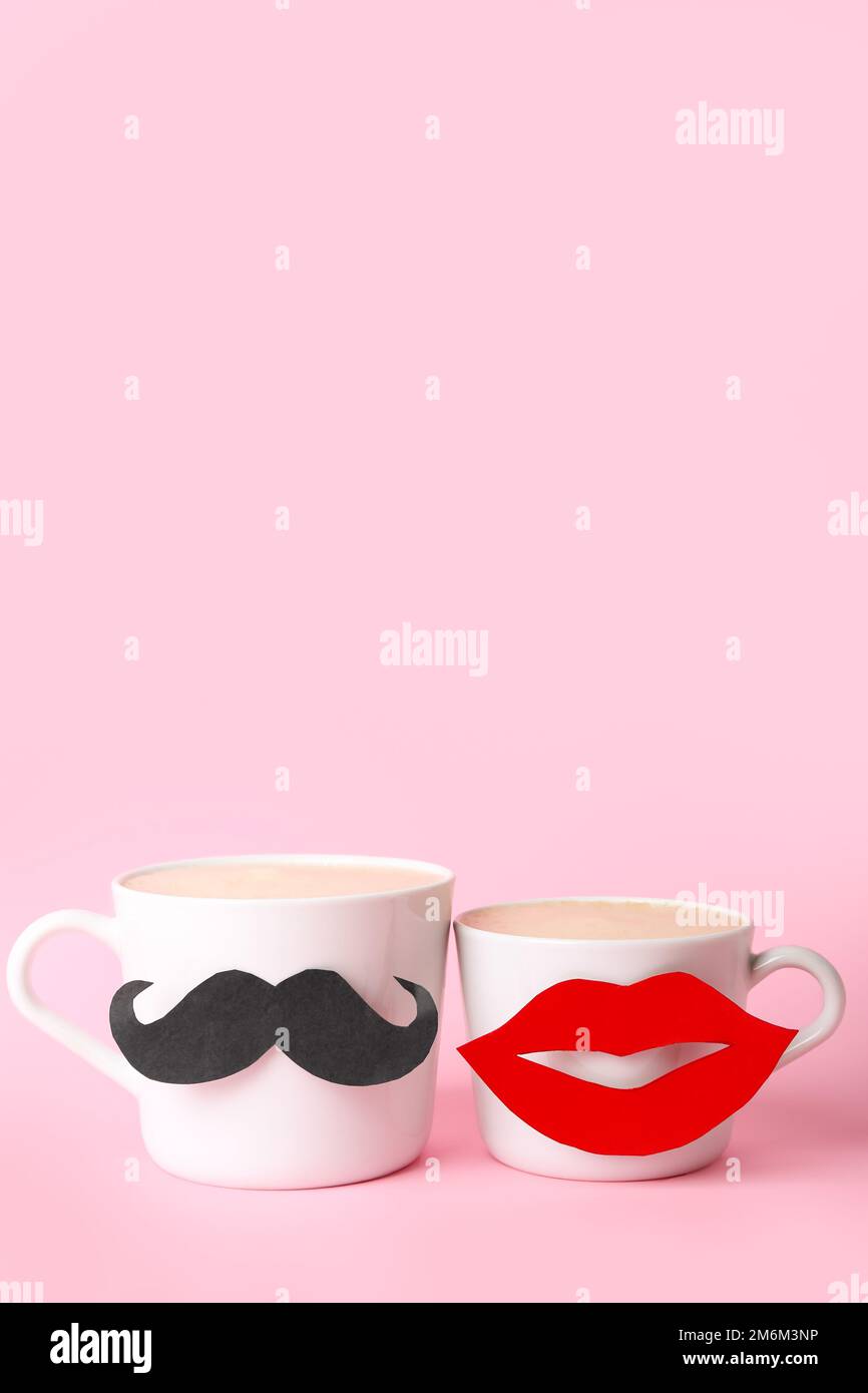 Cups of coffee with paper moustache and lips on pink background ...