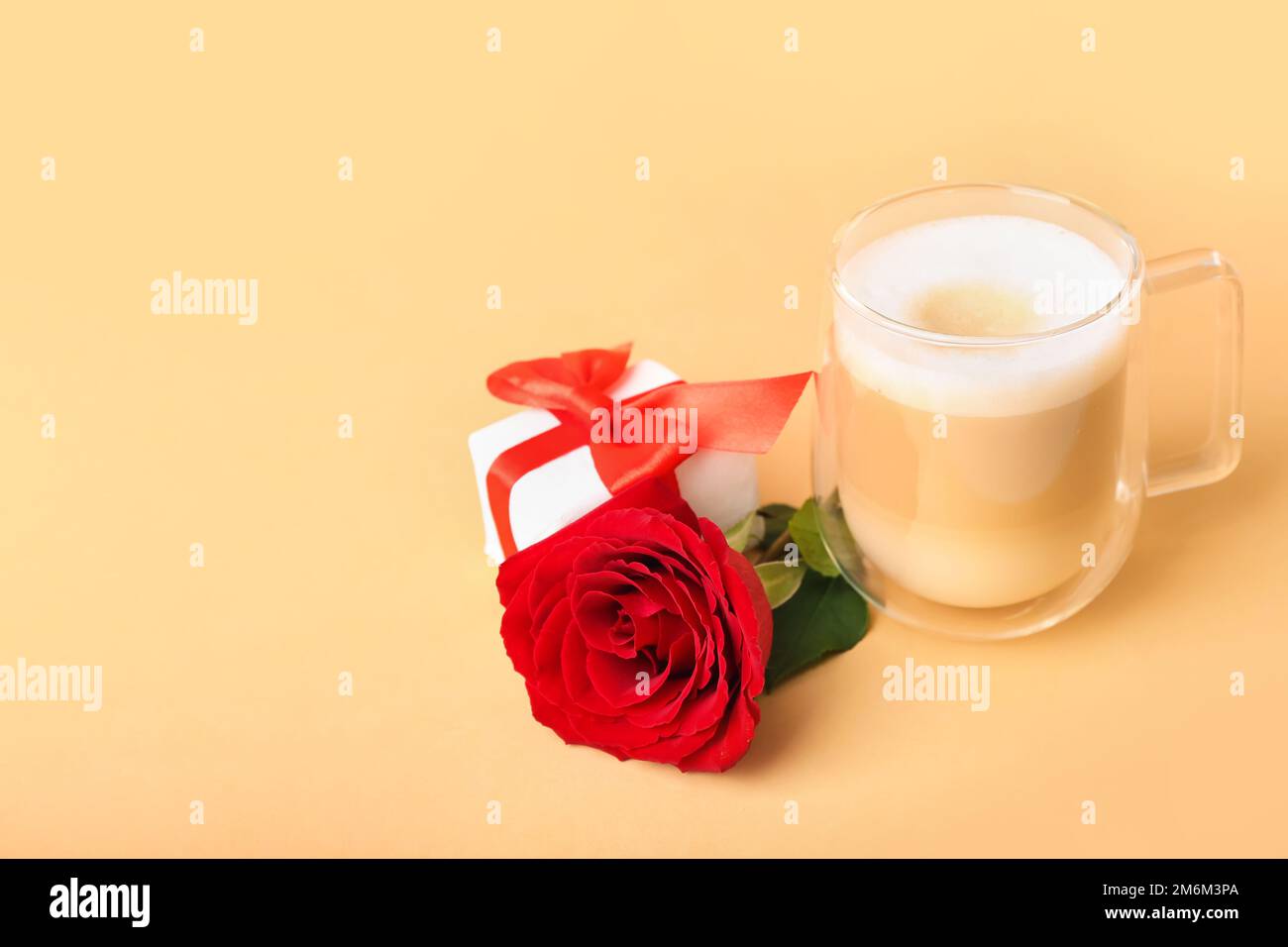 Glass cup of latte, gift and rose on beige background. Valentine's Day ...