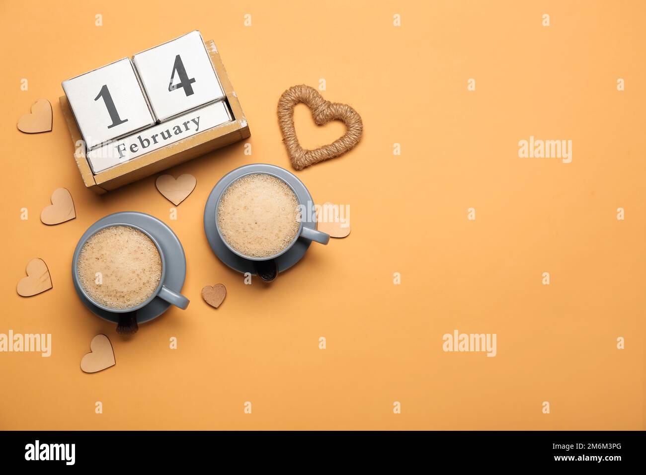 Calendar with date 14 FEBRUARY, cups of latte and hearts on beige ...