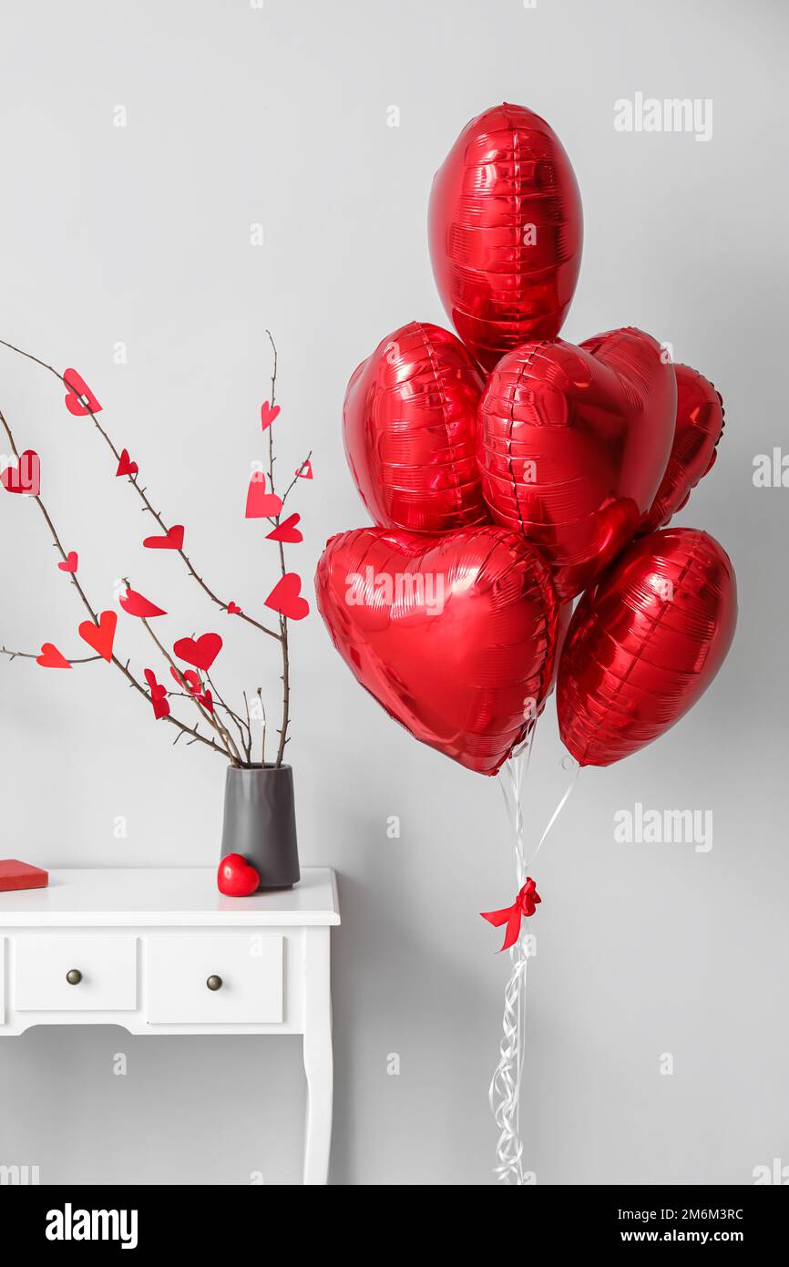 Vase with tree branches on table and heart-shaped balloons for ...