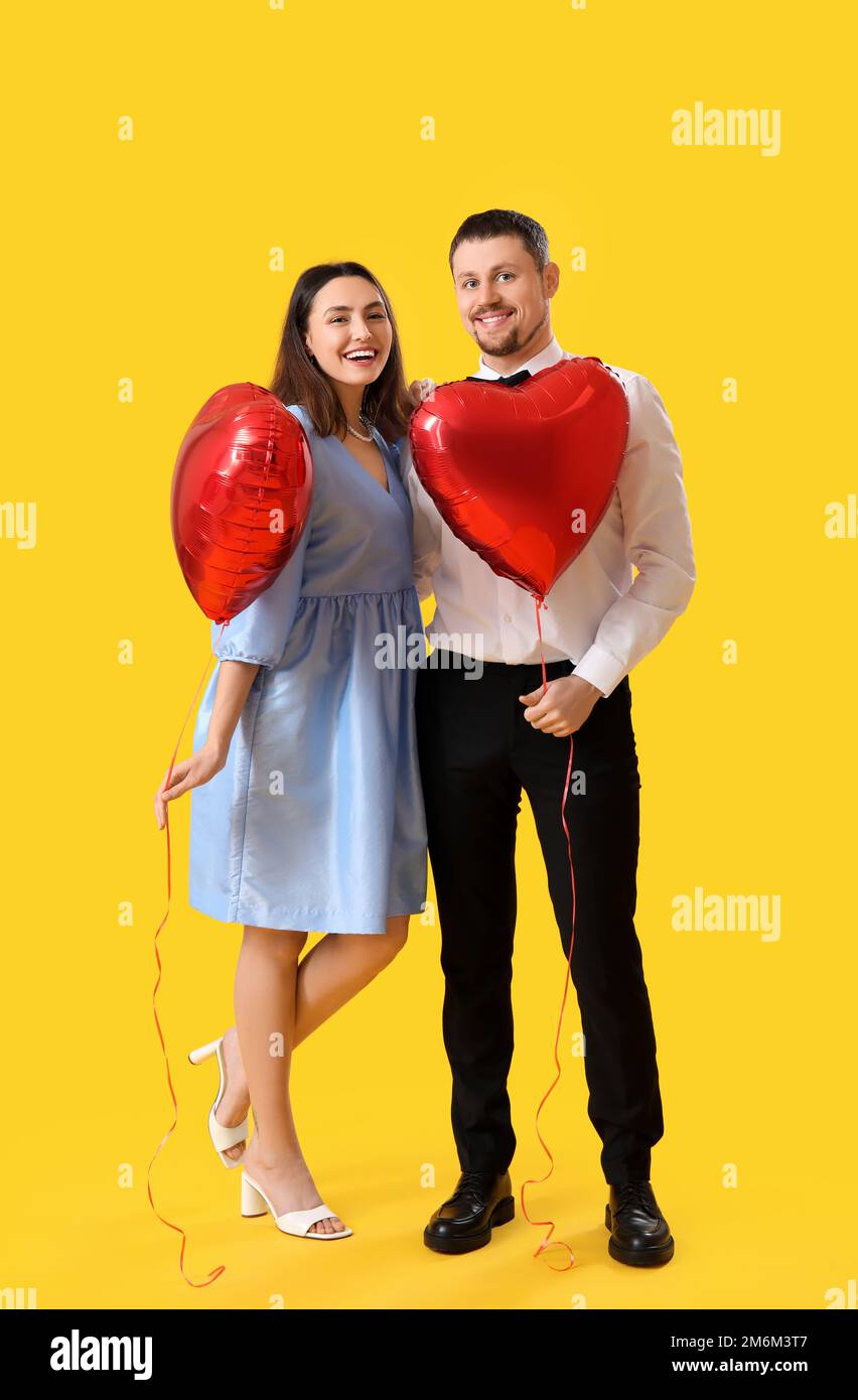 Happy couple in love with balloons on yellow background. Valentine's ...