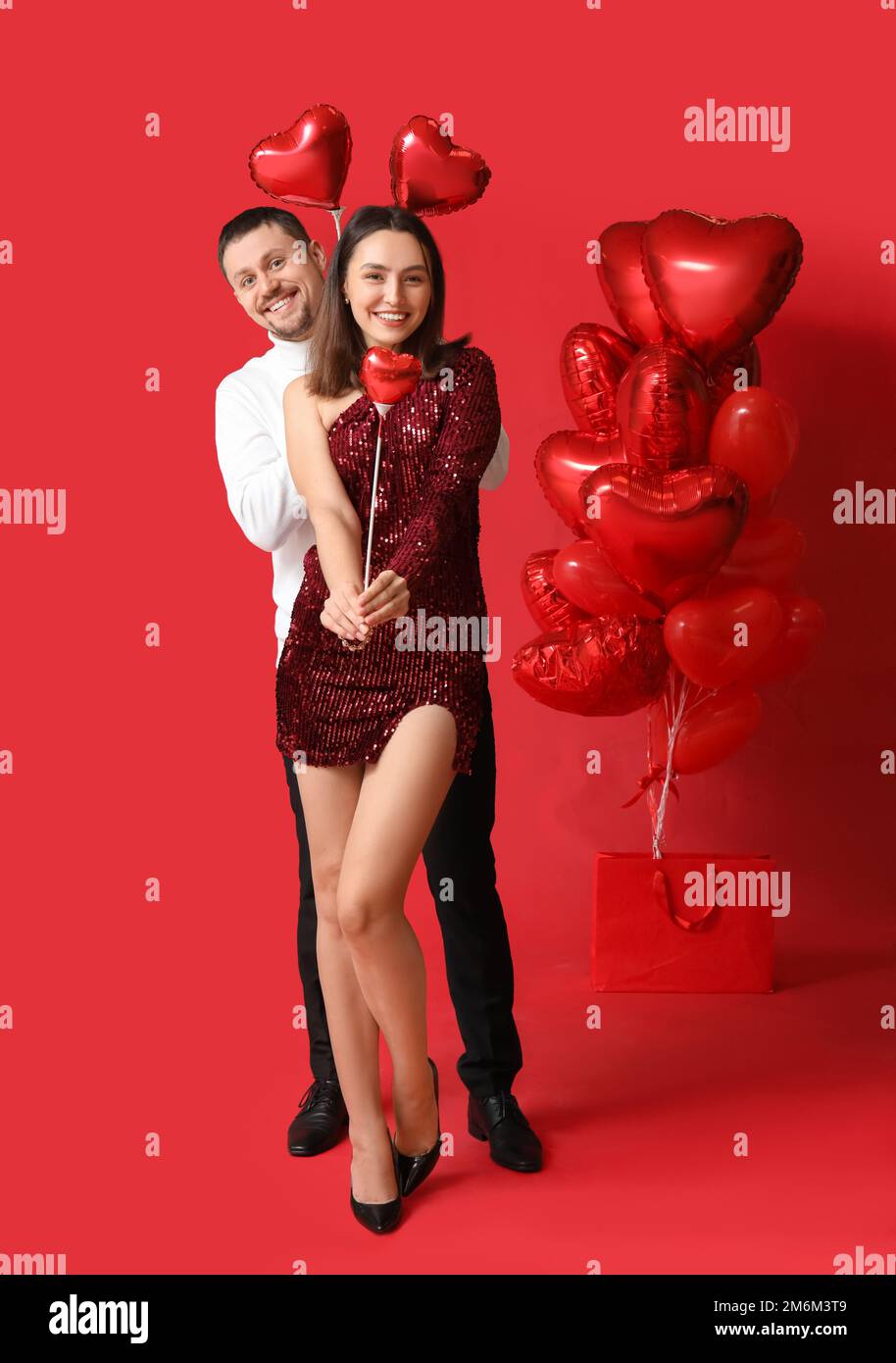 Happy couple in love with balloons on red background. Valentine's Day ...