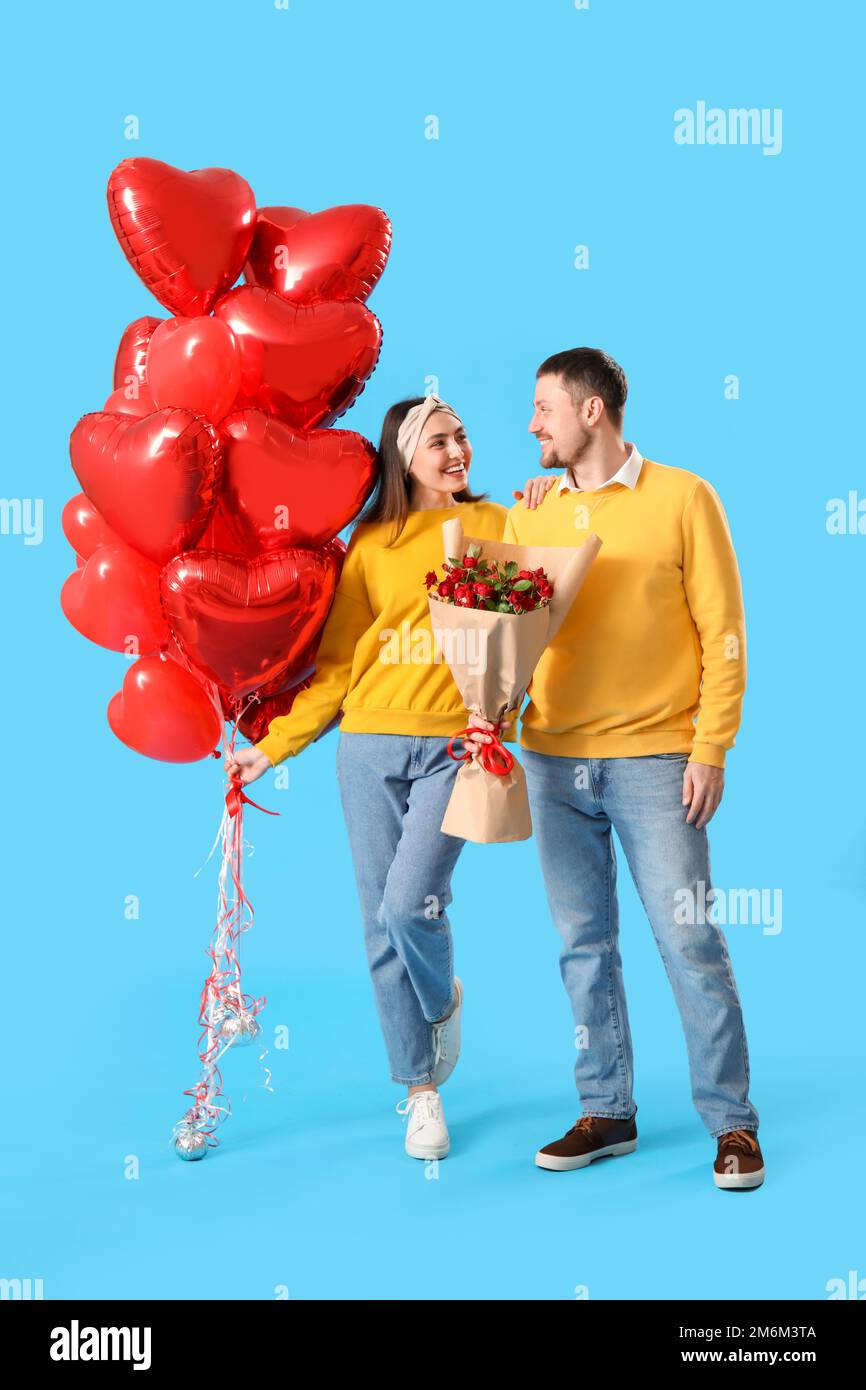 Happy couple in love with roses and balloons on blue background ...