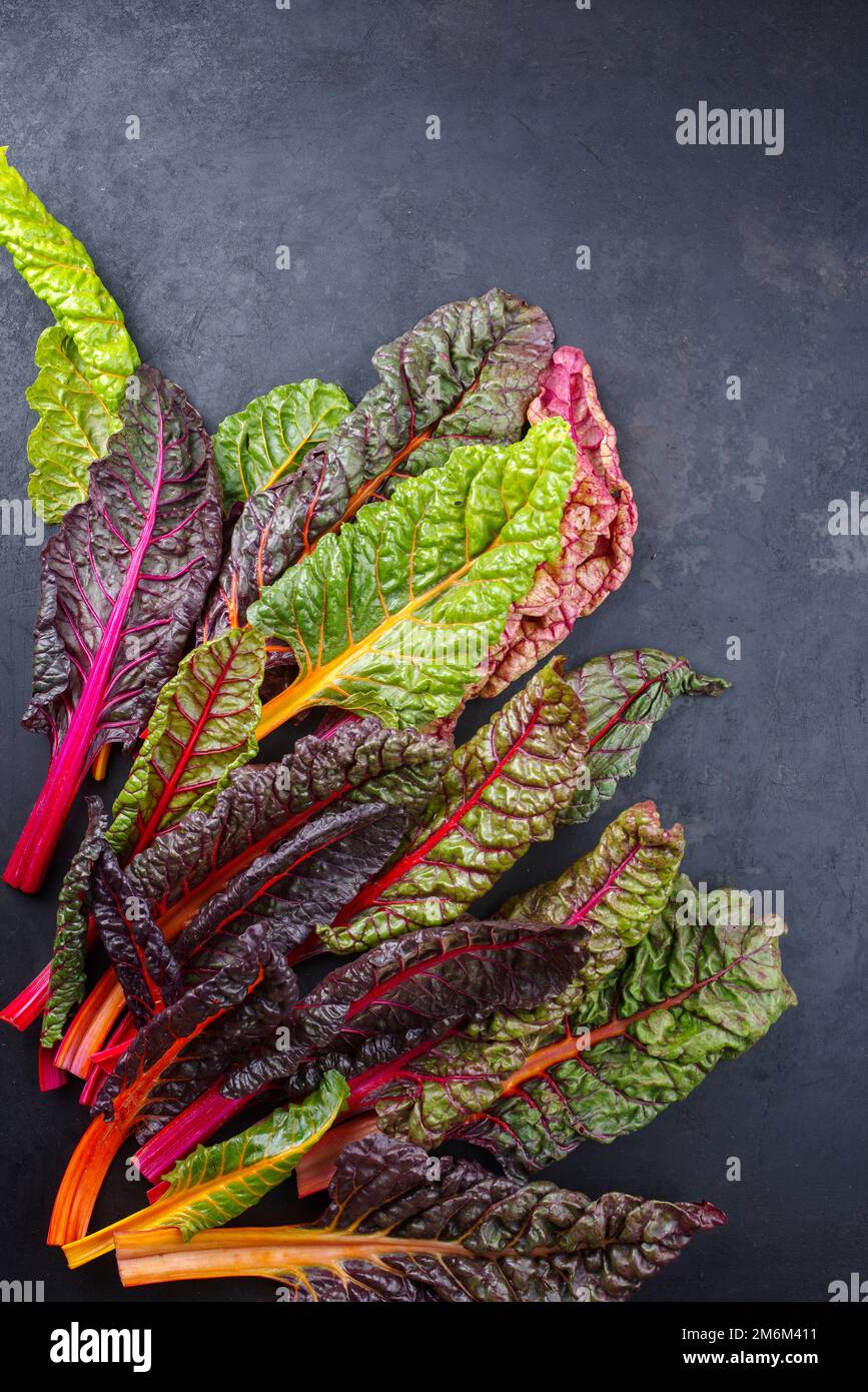 Raw colourful chard offered as top view on a rustic black board with ...