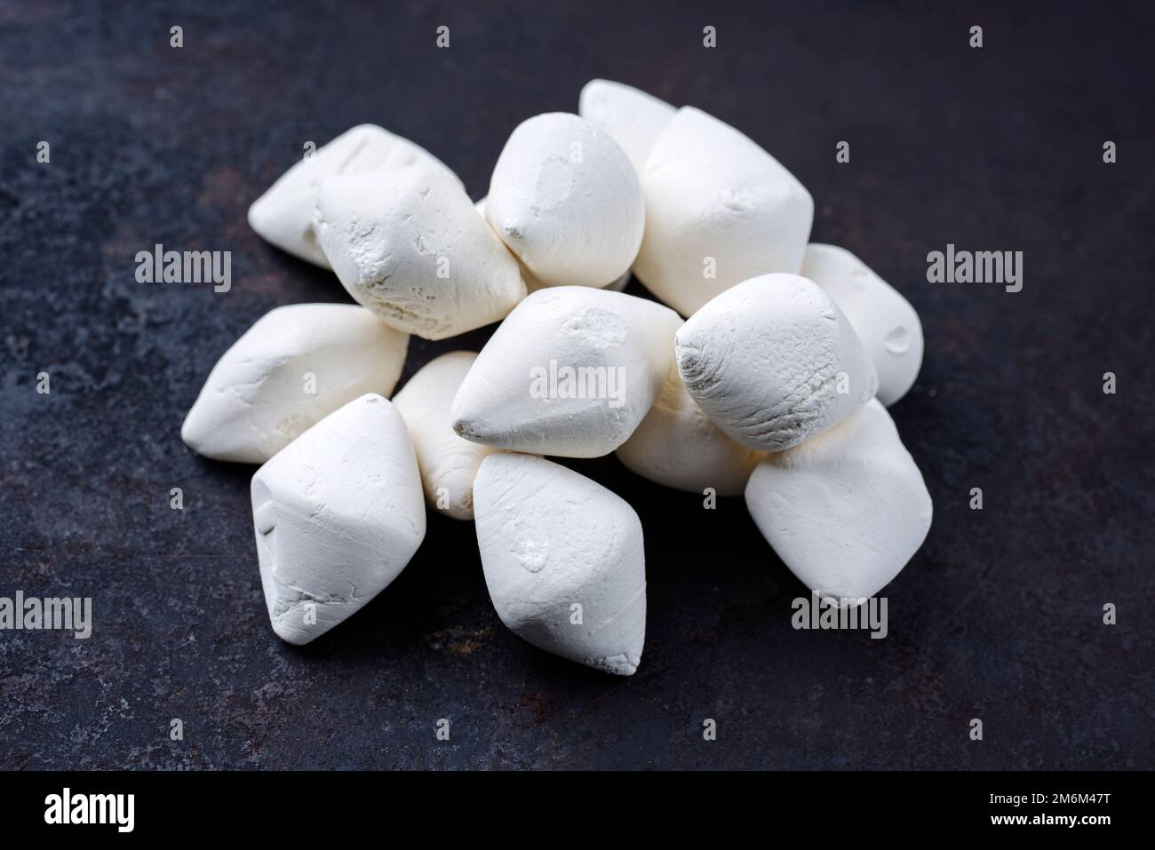Traditional Afghan dried curd kashk pieces as close-up on black rustic ...