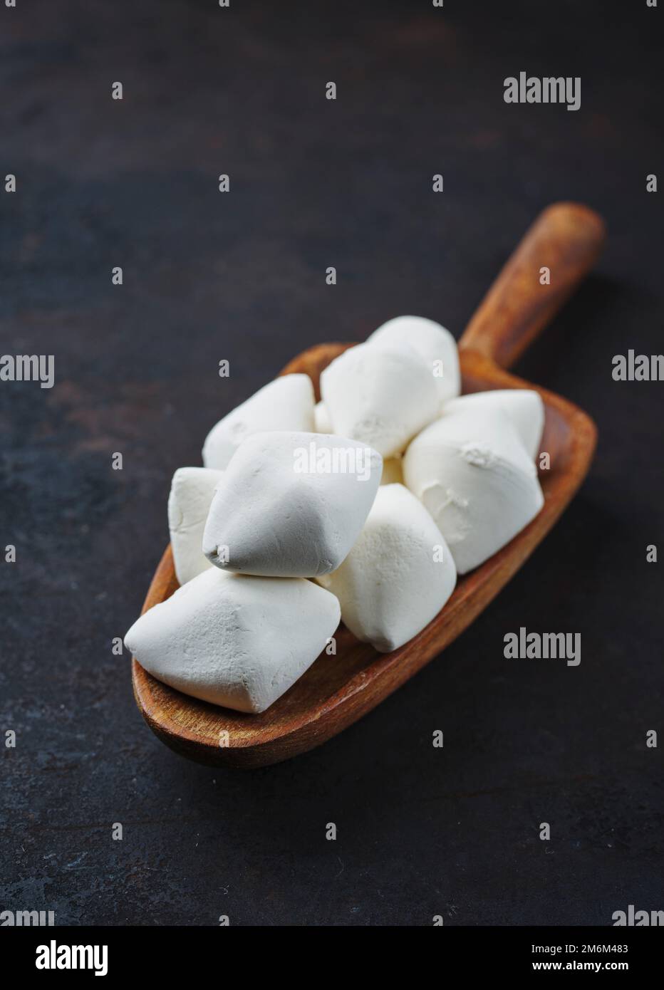 Traditional Afghan dried curd kashk pieces on a small wooden shovel as ...