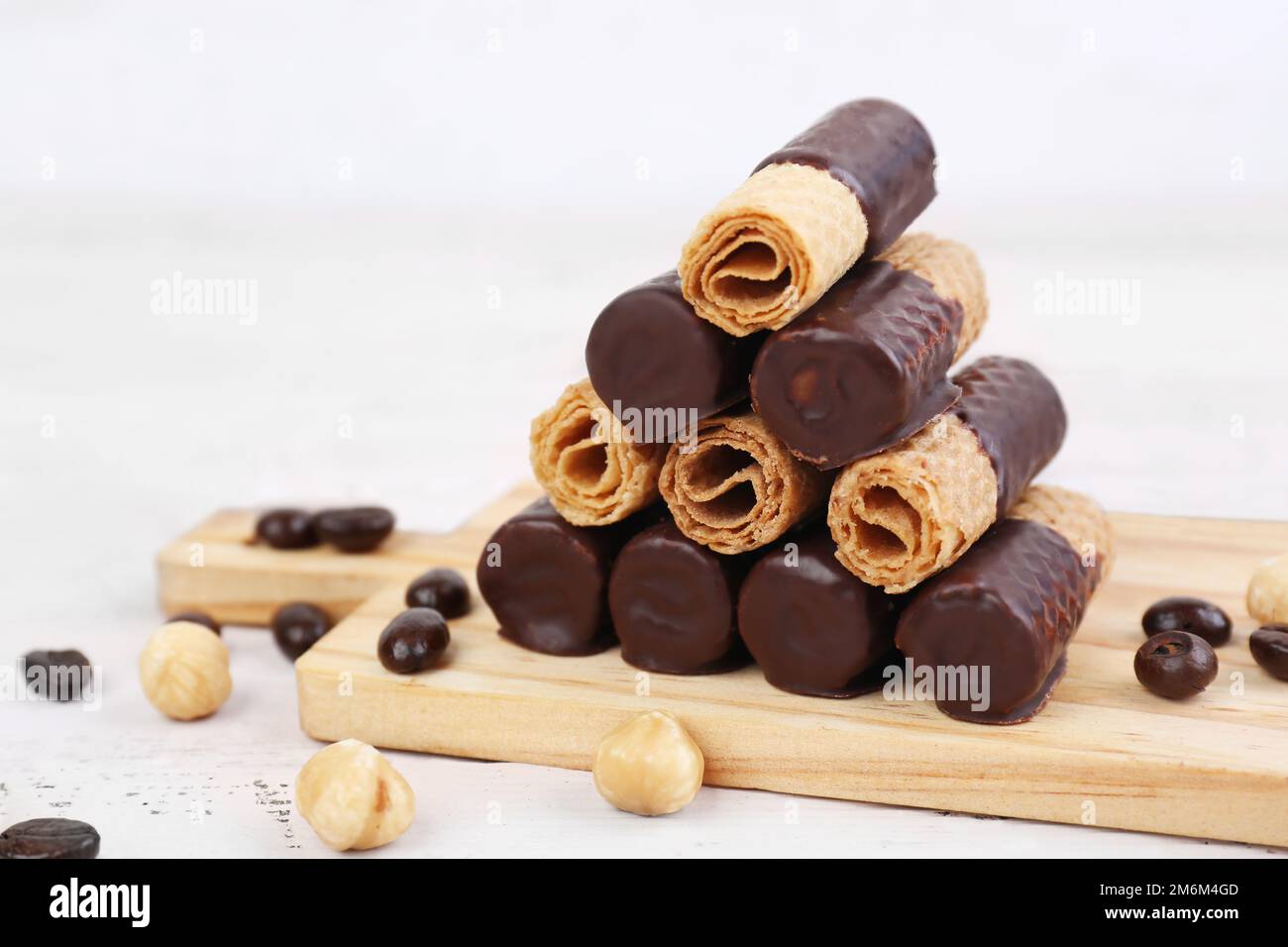 Cutting board with heap of delicious wafer rolls, nuts and coffee beans ...