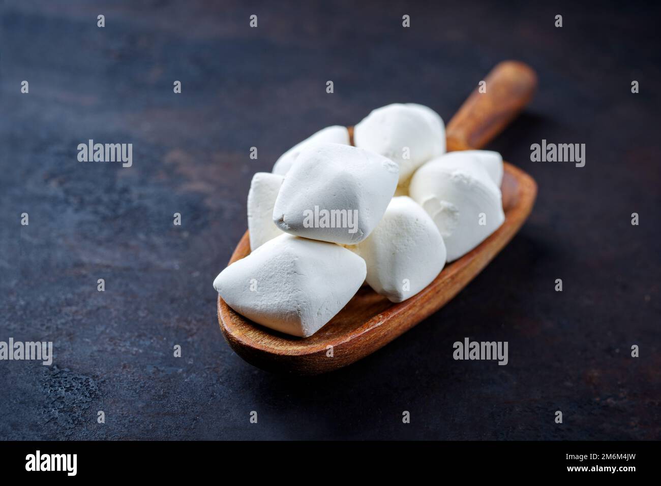 Traditional Afghan dried curd kashk pieces on a small wooden shovel as ...
