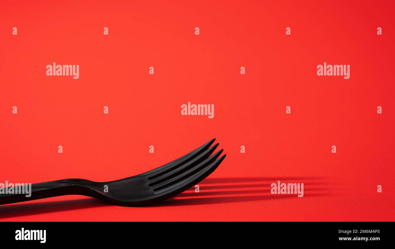 Black fork on a red background Stock Photo - Alamy