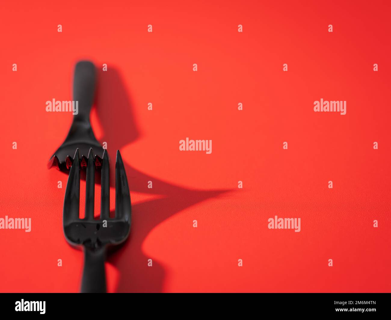 Black fork on a red background Stock Photo - Alamy