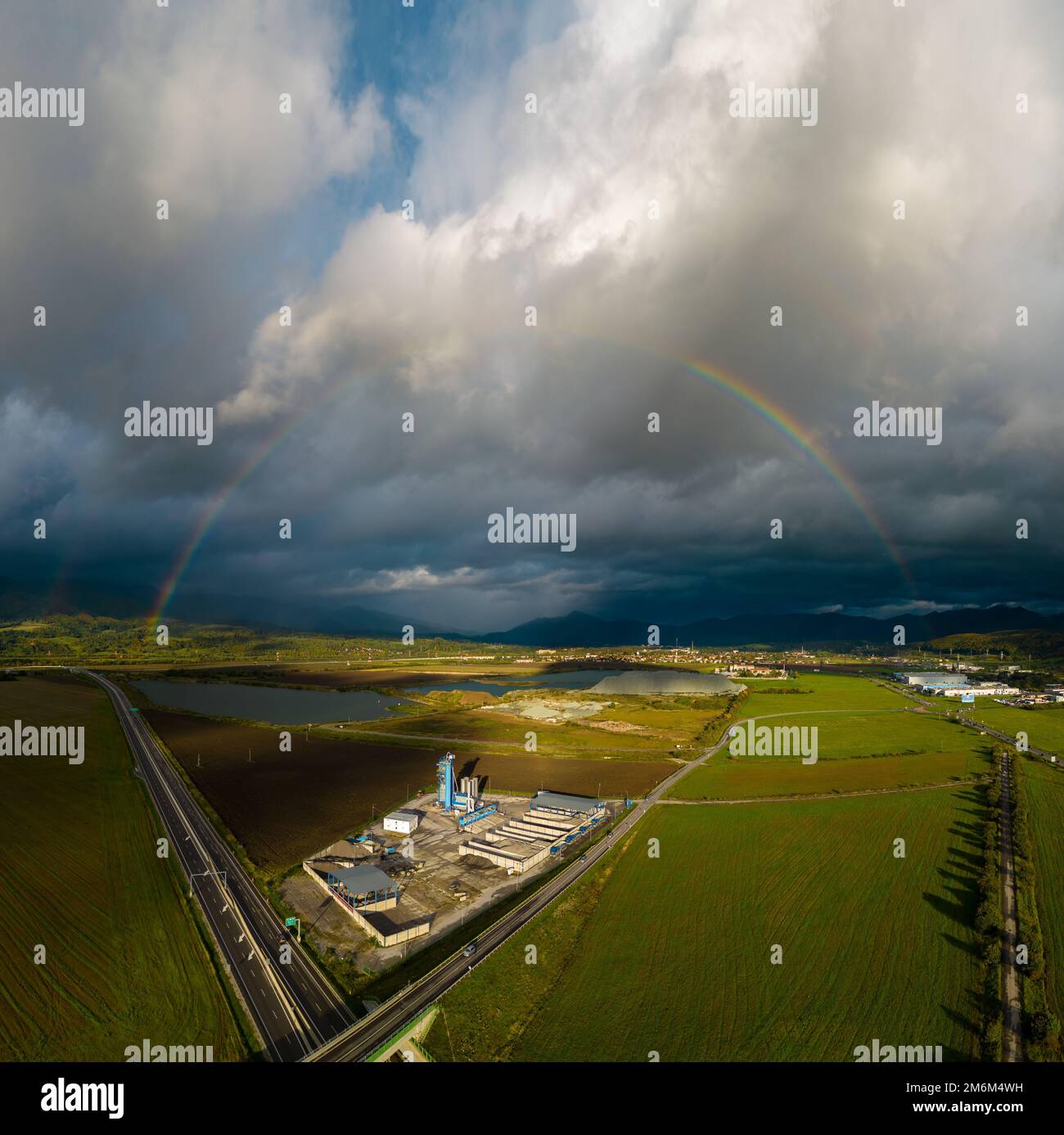 A bird's eye view of a factory in green cultivated fields under a ...