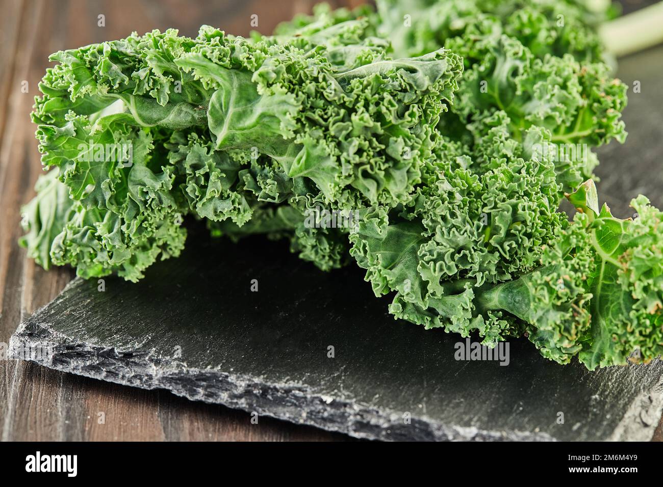 Curled lettuce on black stone on wooden background. Close up Stock ...