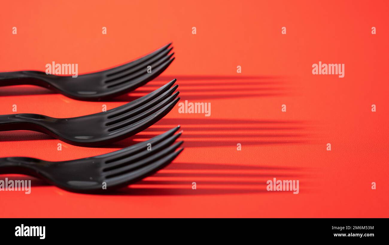 Black fork on a red background Stock Photo - Alamy