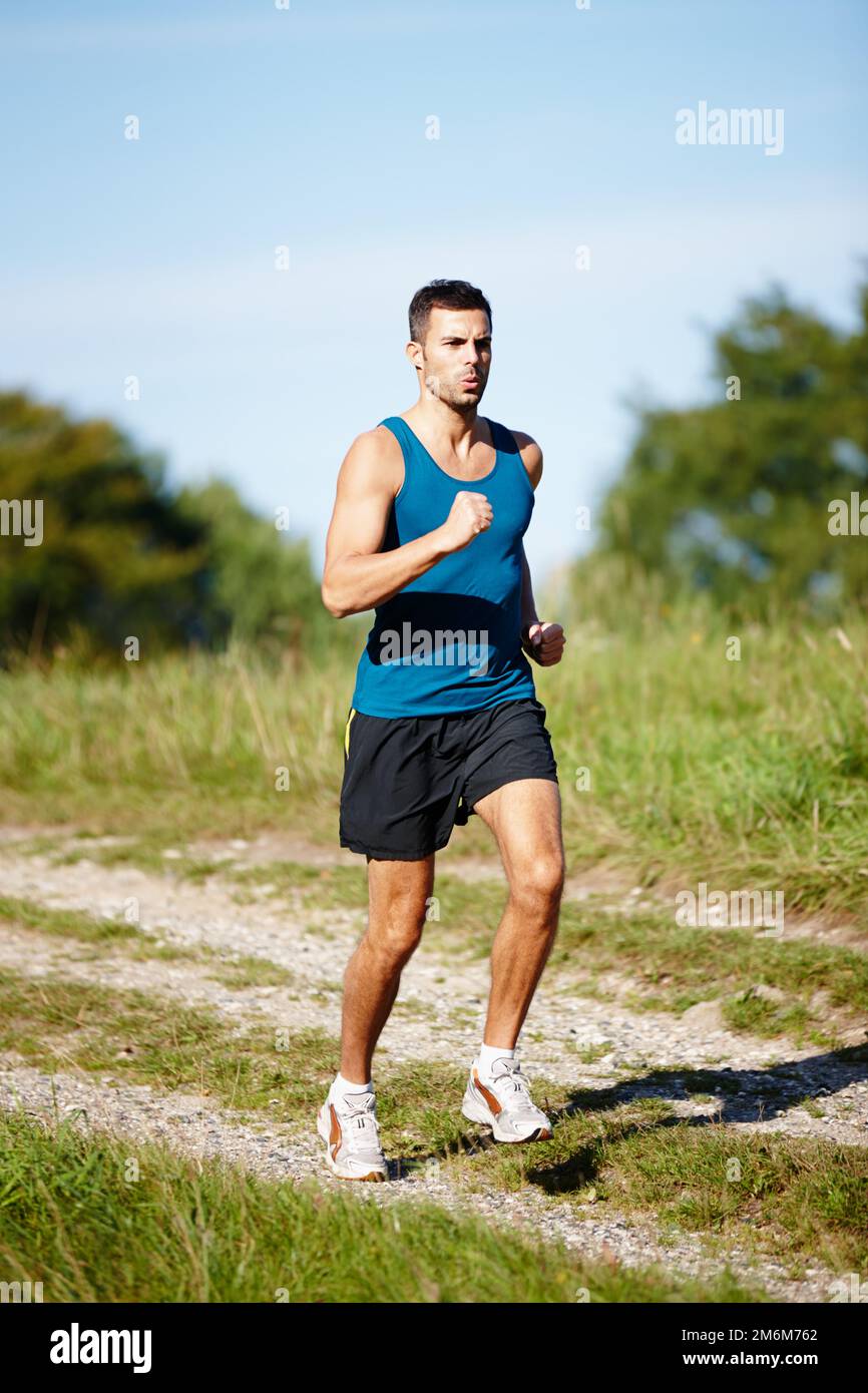 Powering through the pain. a handsome young man taking a jog outdoors ...
