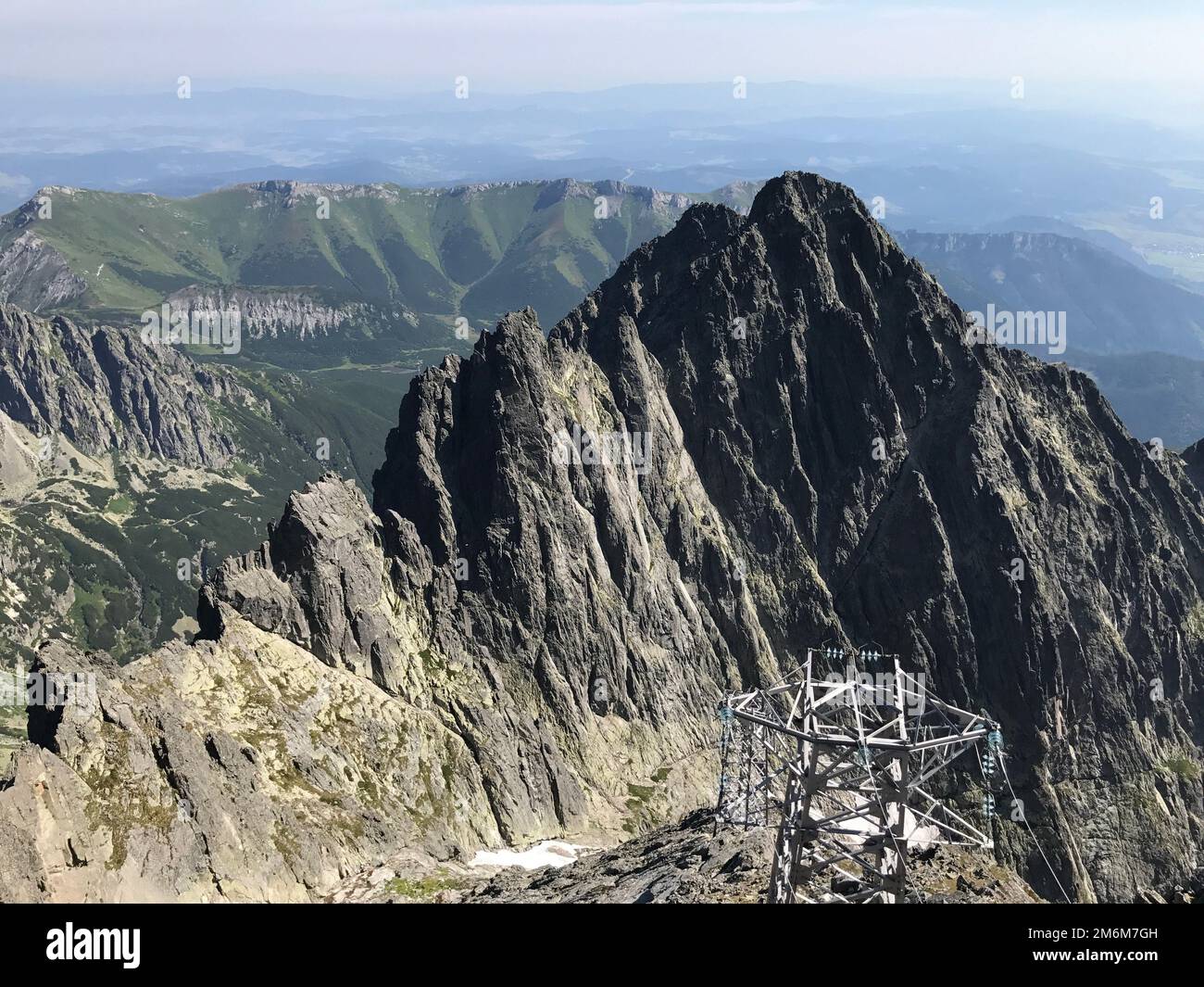 A bird's eye view of a utility pole on top of rocky mountains on a ...