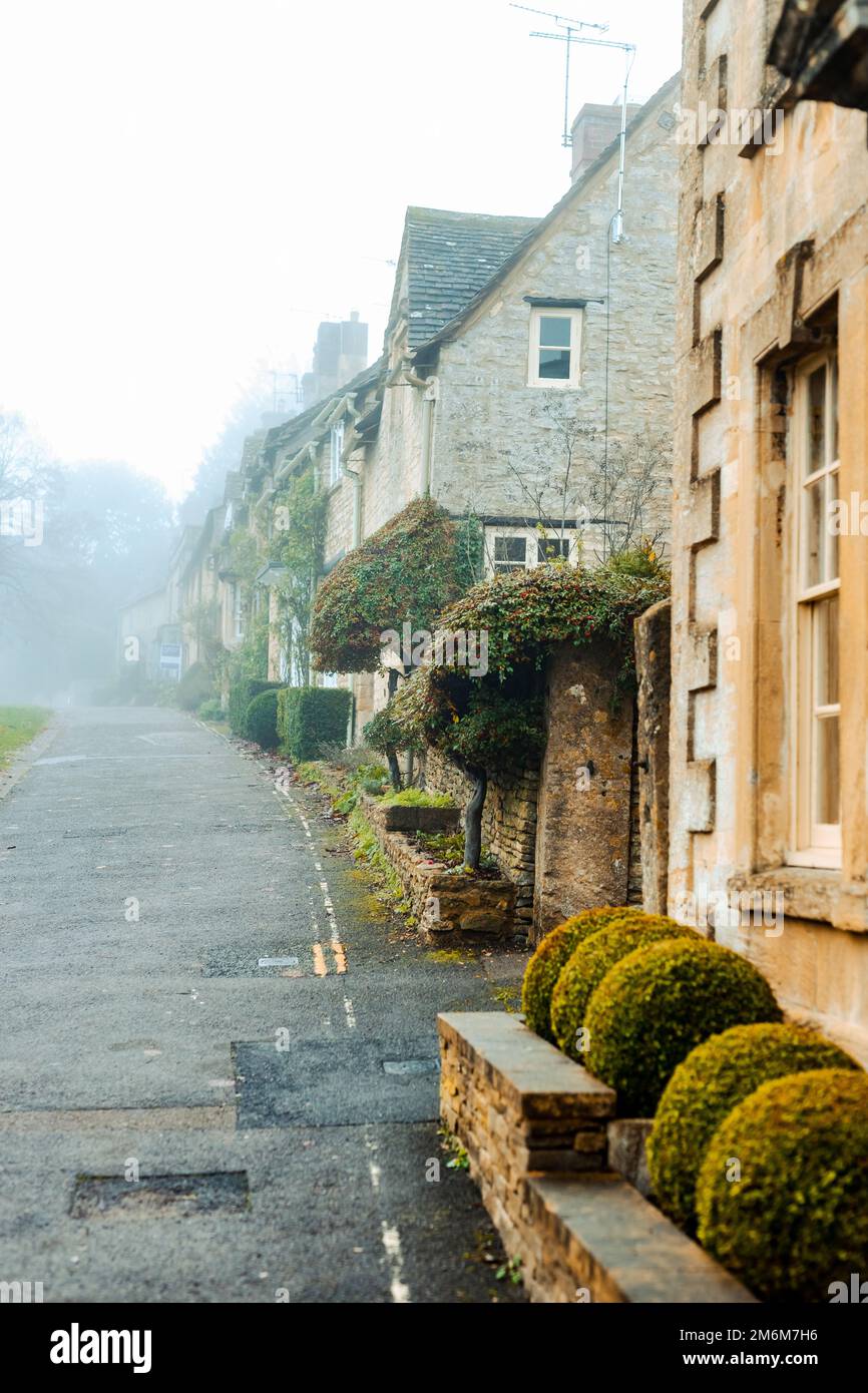 A vertical of old houses along a narrow street on a foggy day in ...