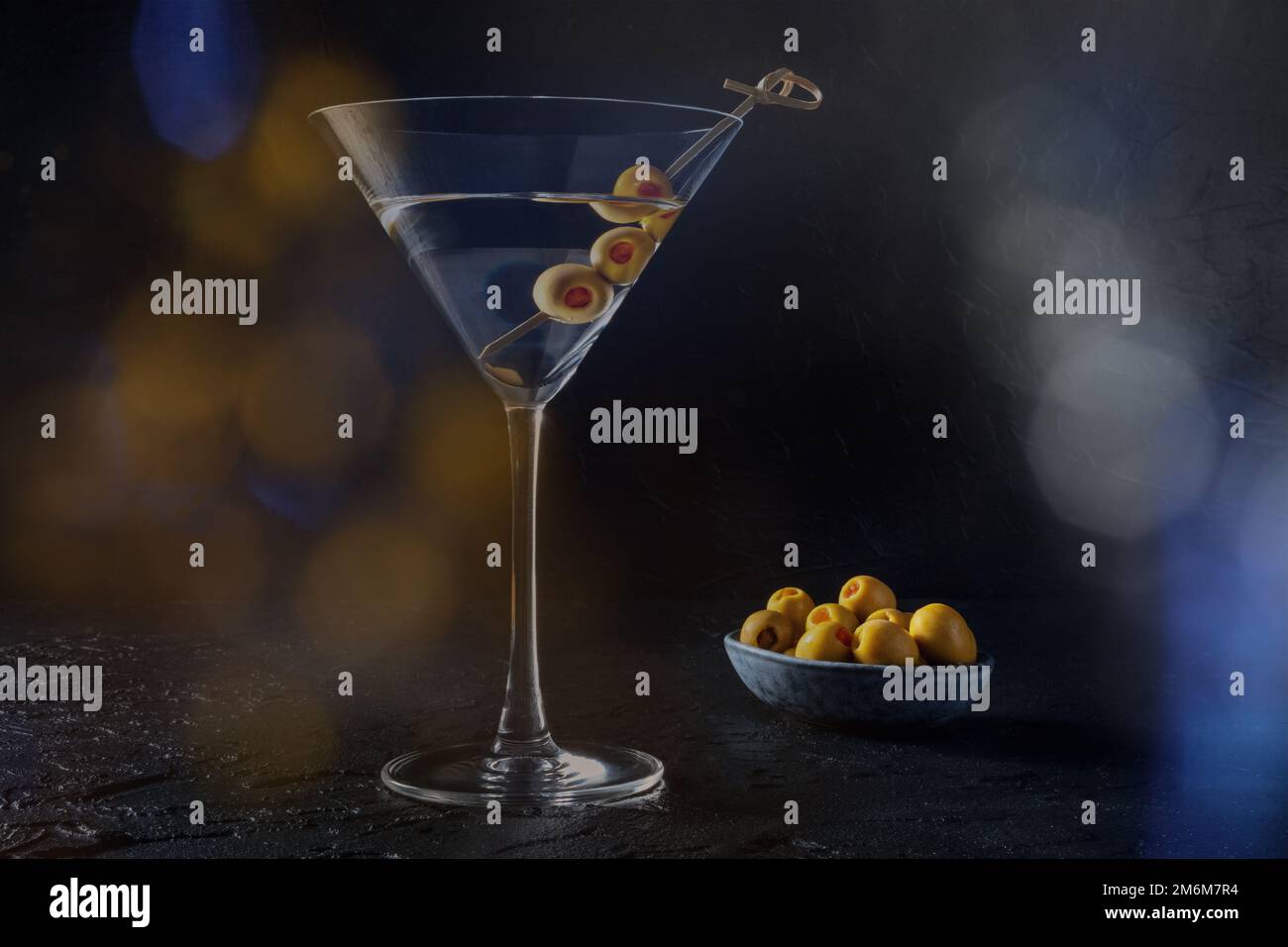 Martini, a glass with spicy olives, on a black background. Alcoholic ...