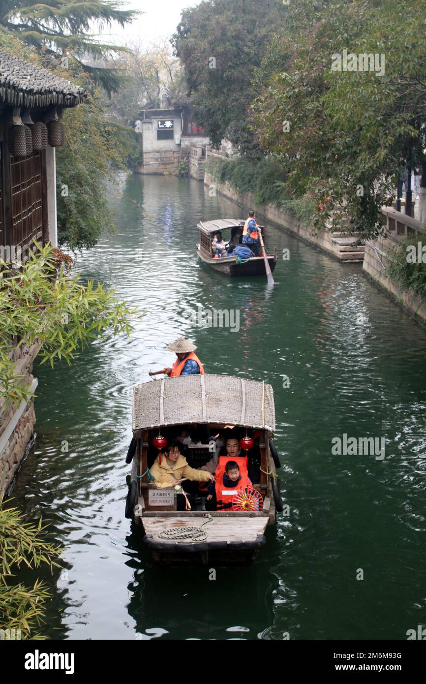 Tourists take a small wooden rowboat on the water in Pingjiang Road ...