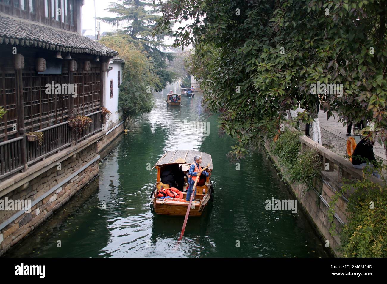 Tourists take a small wooden rowboat on the water in Pingjiang Road ...