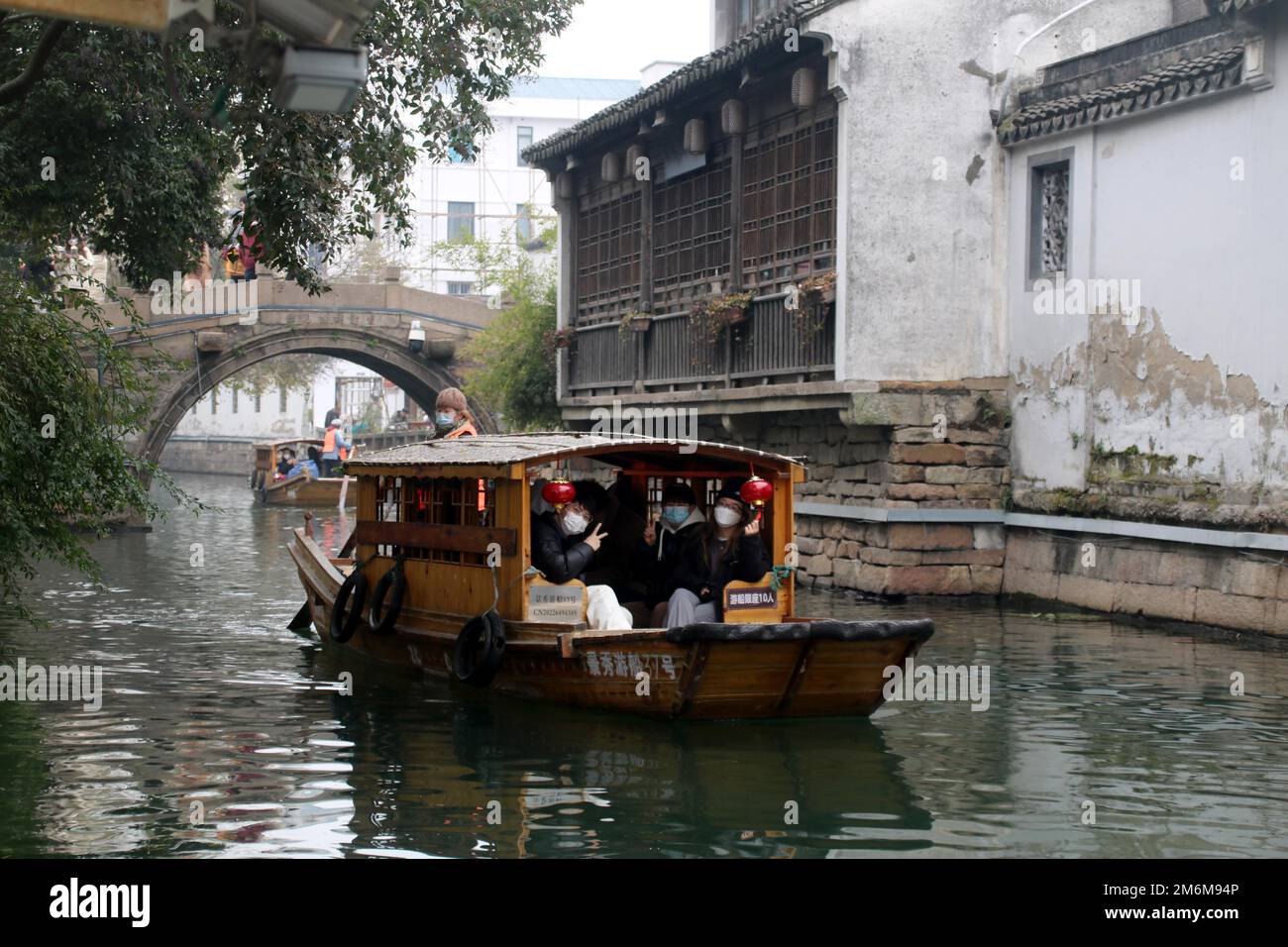 Tourists take a small wooden rowboat on the water in Pingjiang Road ...