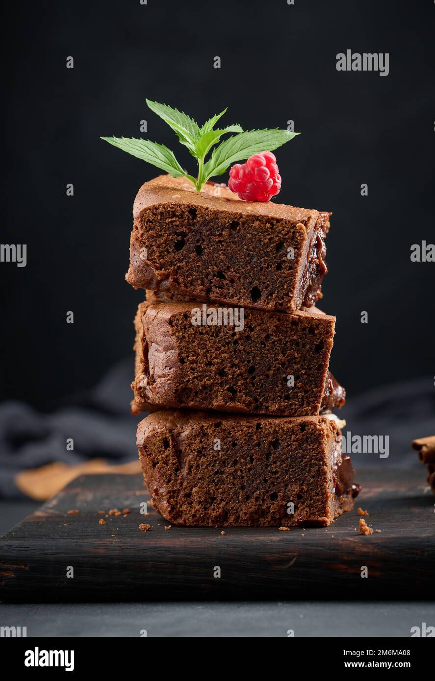 Baked pieces of chocolate brownie pie on black table, delicious dessert ...