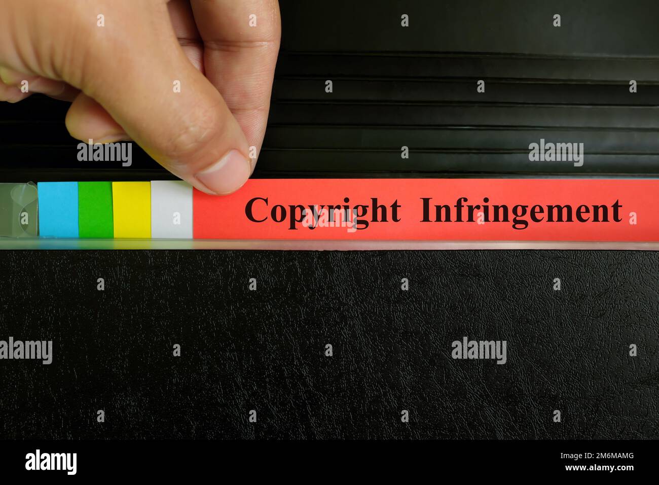Hand picking copyright infringement file record in black binder folder ...