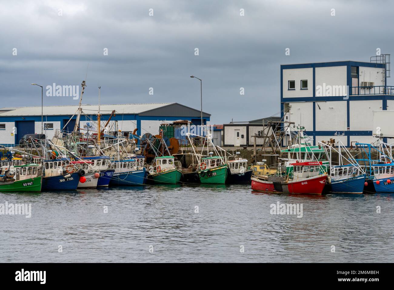 Colorful fishing boats and trawlers in the sheltered port and harbor of ...