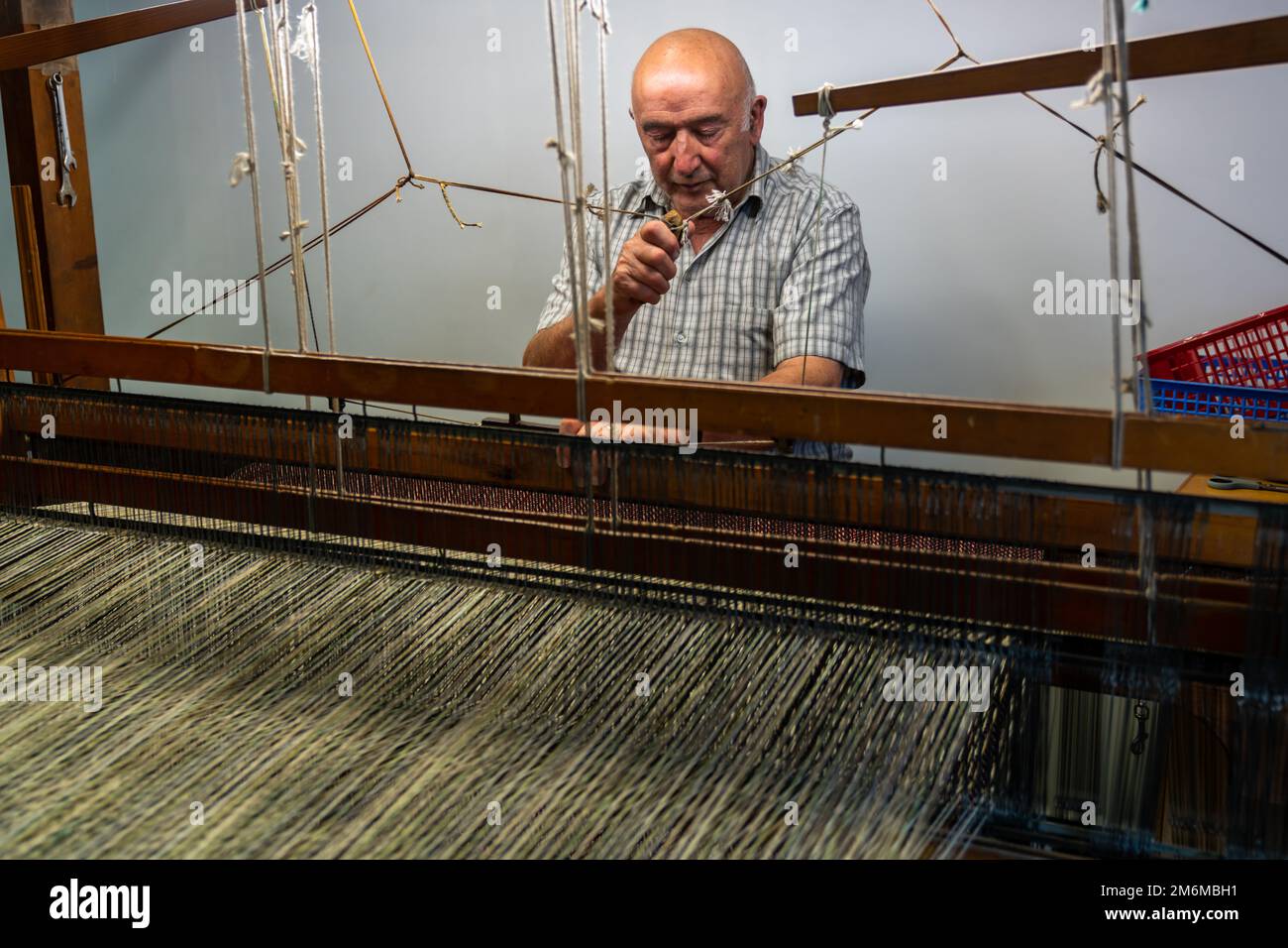 Master craftsman working on a traditional wooden loom and hand weaving ...
