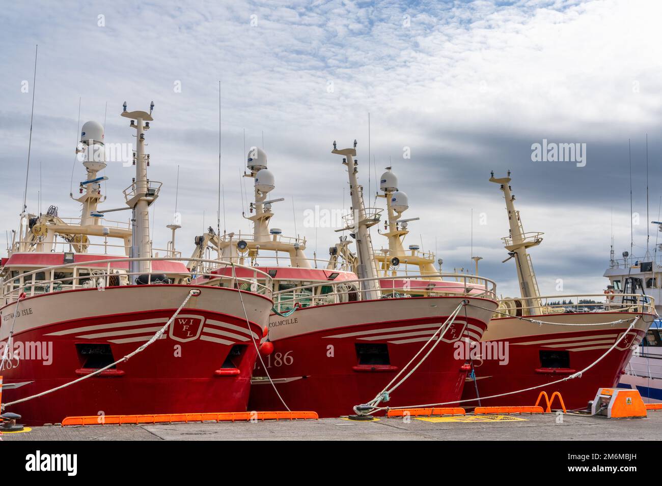 Three red fishing trawlers in the large industrial fishing port of ...